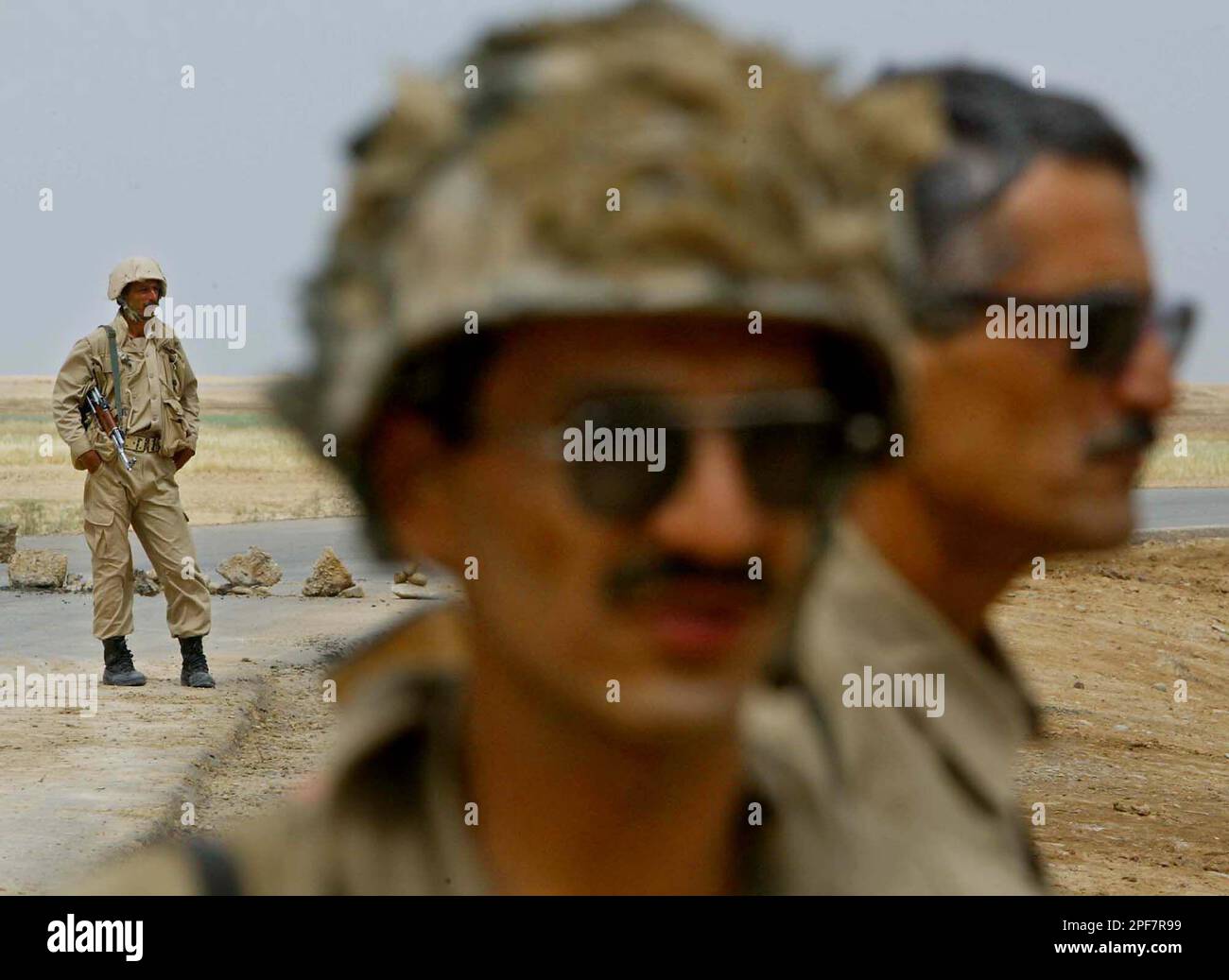 Fighters of the Mujahedin Khalq (MKO) stand guard on a road leading to ...