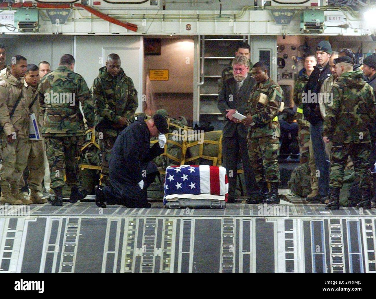 An army priest, center, kneels at the flag-draped coffin of a killed U ...