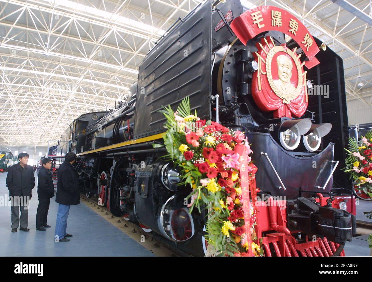 Train fans look at an old steam train decorated with a portrait of the ...