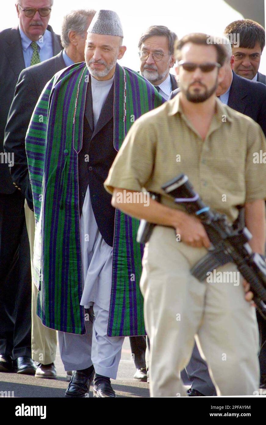 An armed bodyguard walks in front of Afghan President Hamid Karzai ...