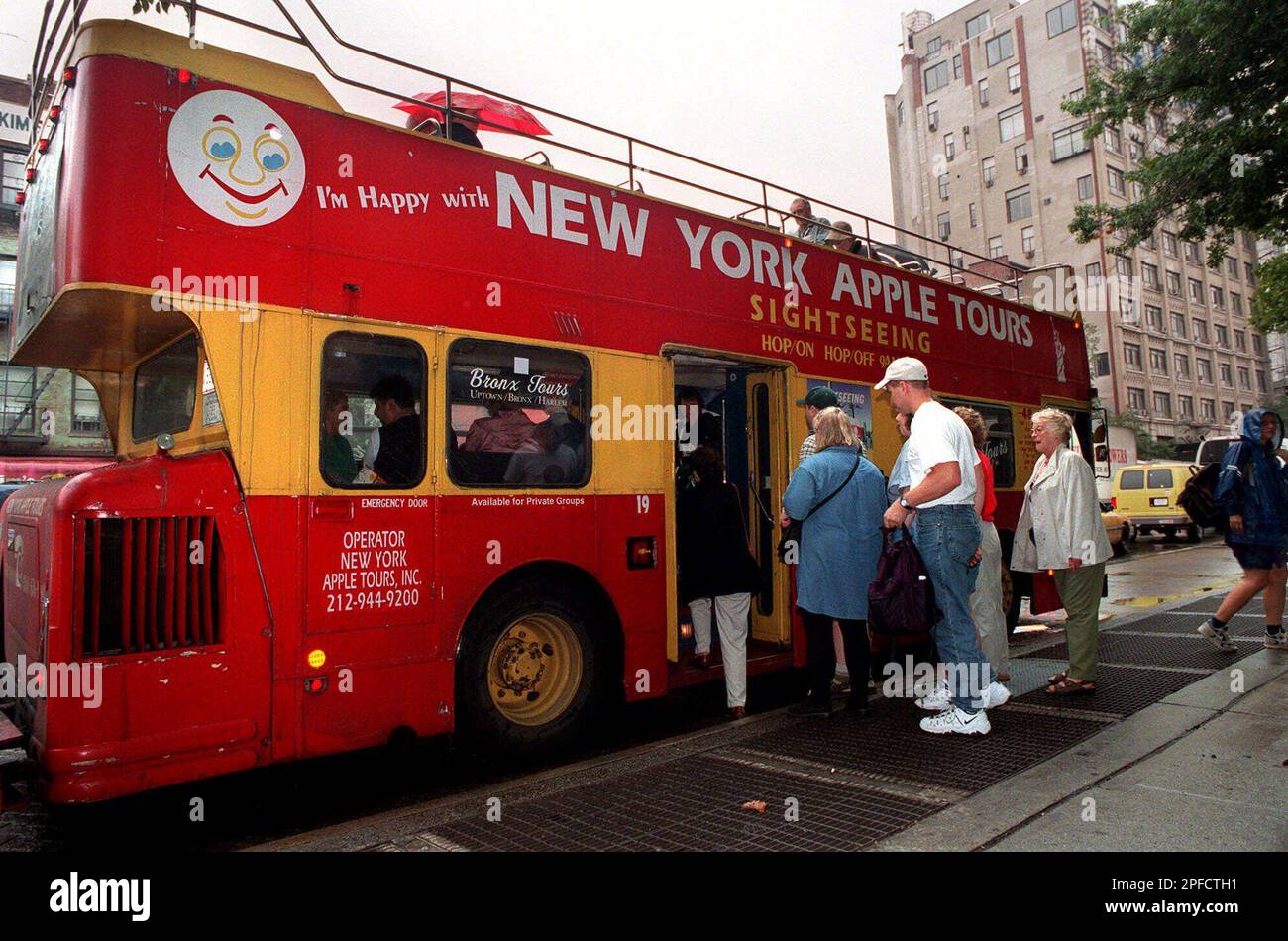 Tourists board a "Big Apple Tours" double-decker bus in the Greenwich ...