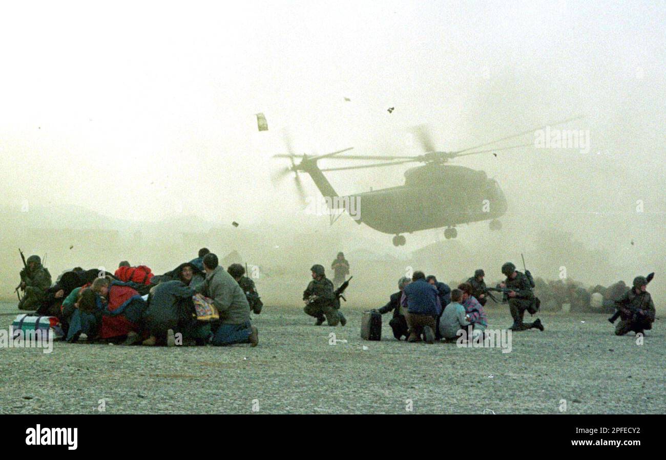People crouch down while German Bundeswehr soldiers and a helicopter ...
