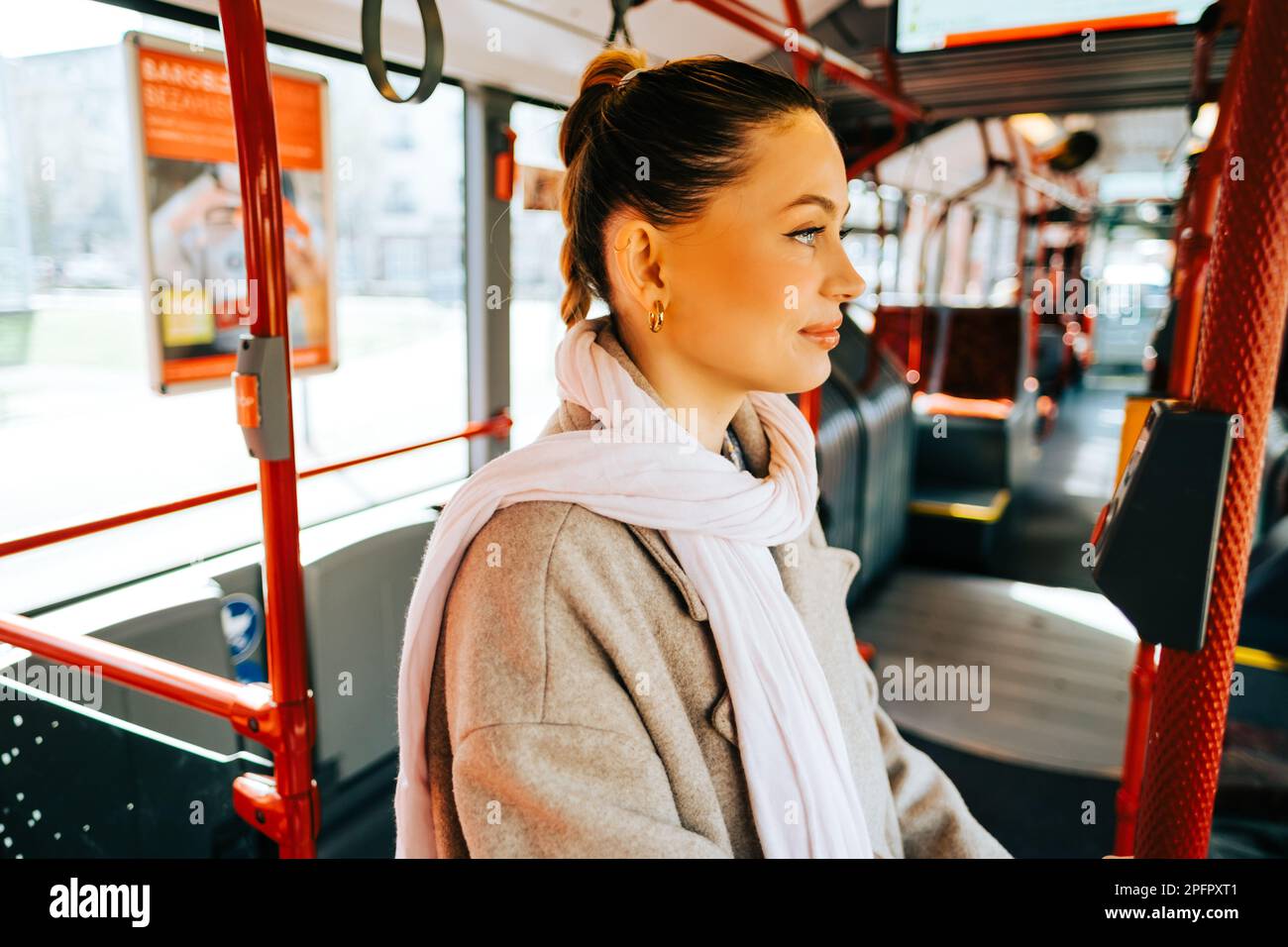 Eine attraktive weiße Frau, die an sonnigen Tagen in einem Bus fährt. Junge, schöne Frau, die ...
