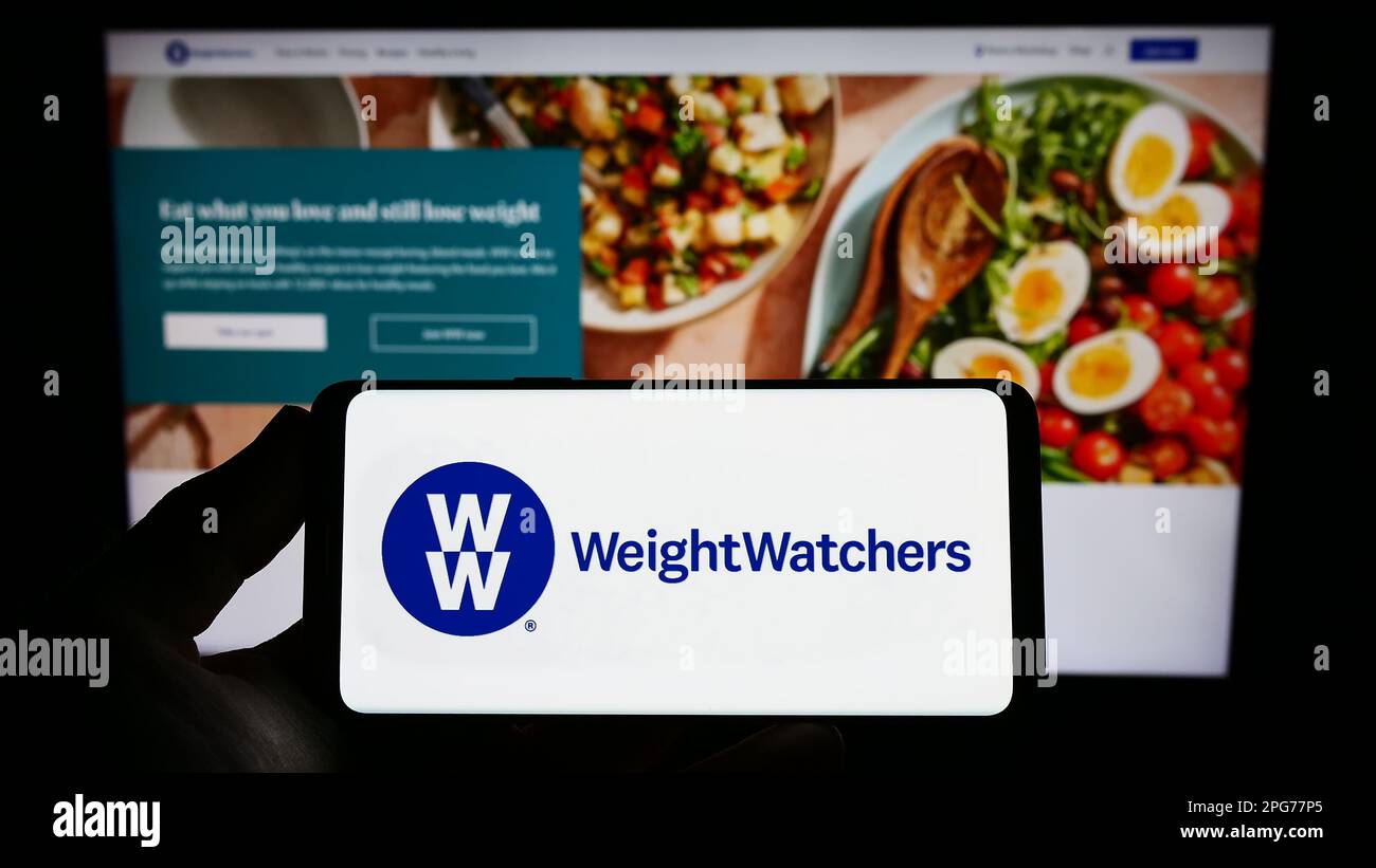 Person, die ein Smartphone mit dem Logo von WW International Inc ...