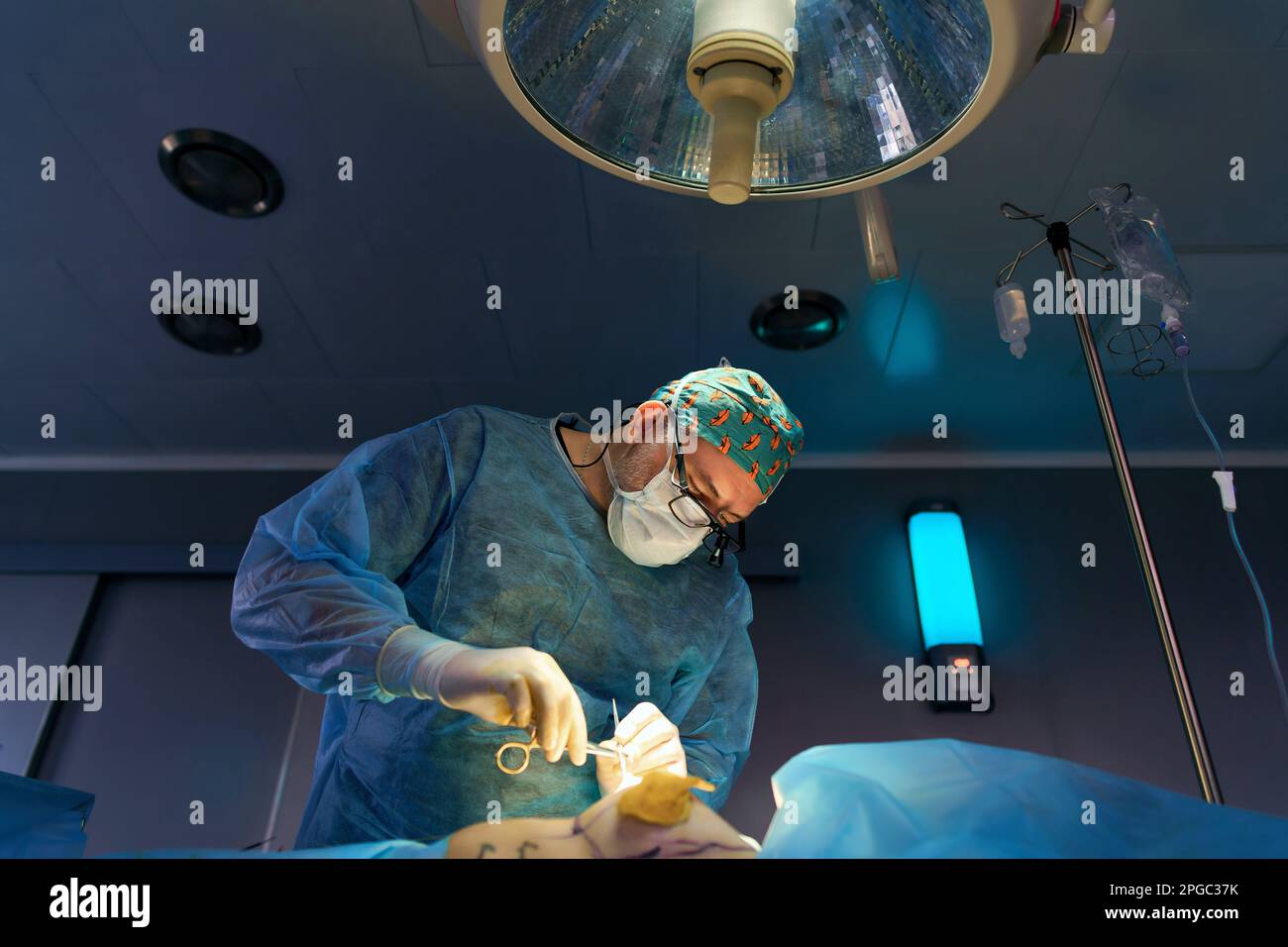 Der Chirurg im Operationssaal steht am Tisch mit dem Patienten unter ...