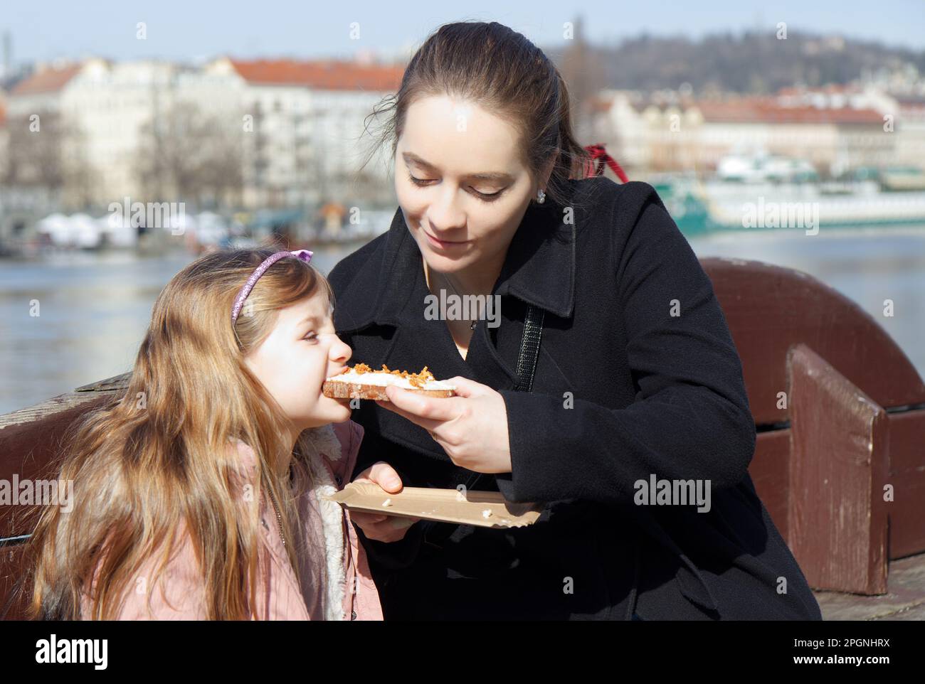 Die junge Mutter und ihre kleine Tochter saßen auf einer Bank am Ufer ...