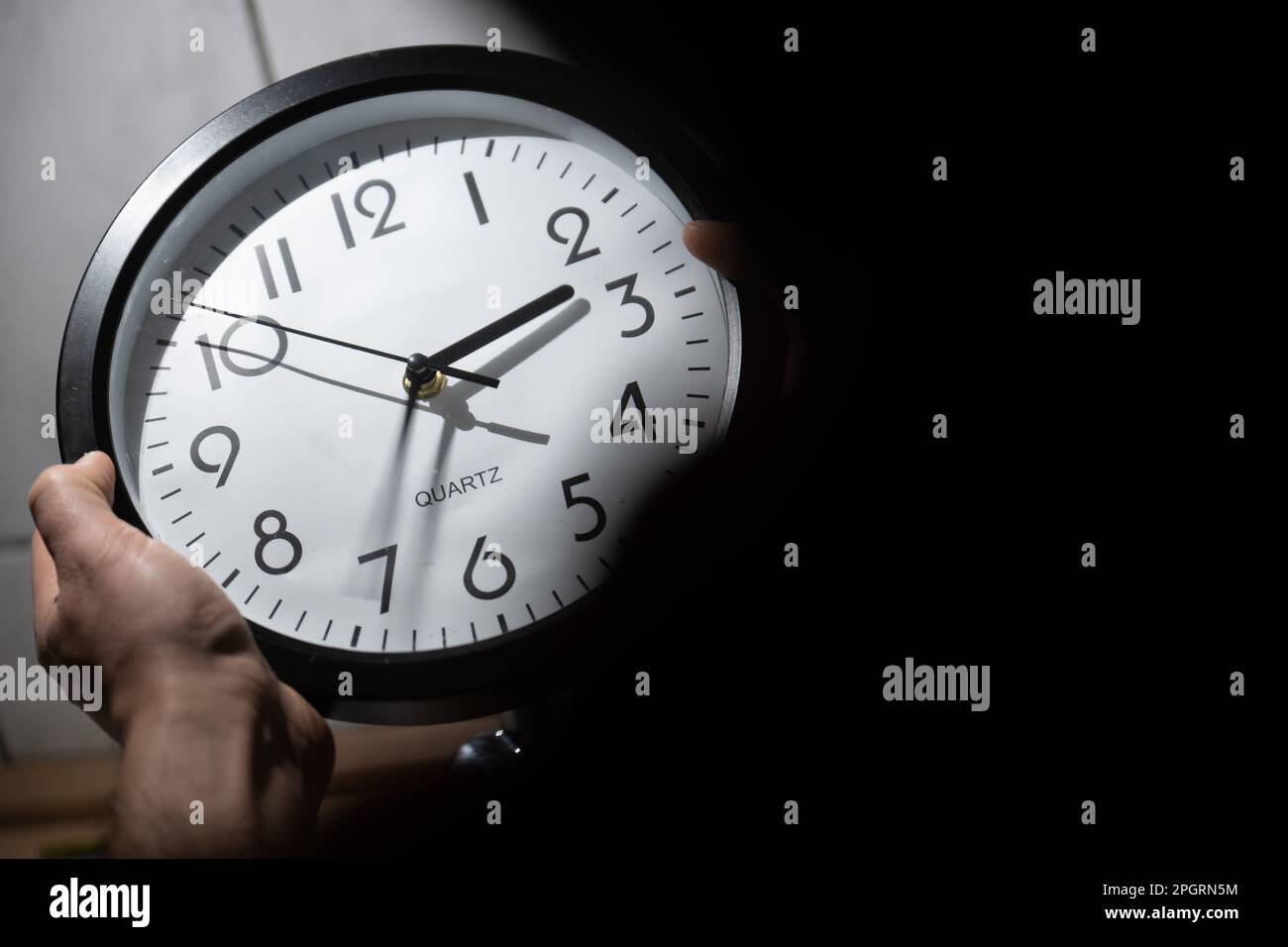 21. März 2023, Hesse, Gießen: Ein Mann stellt eine analoge Uhr von zwei ...