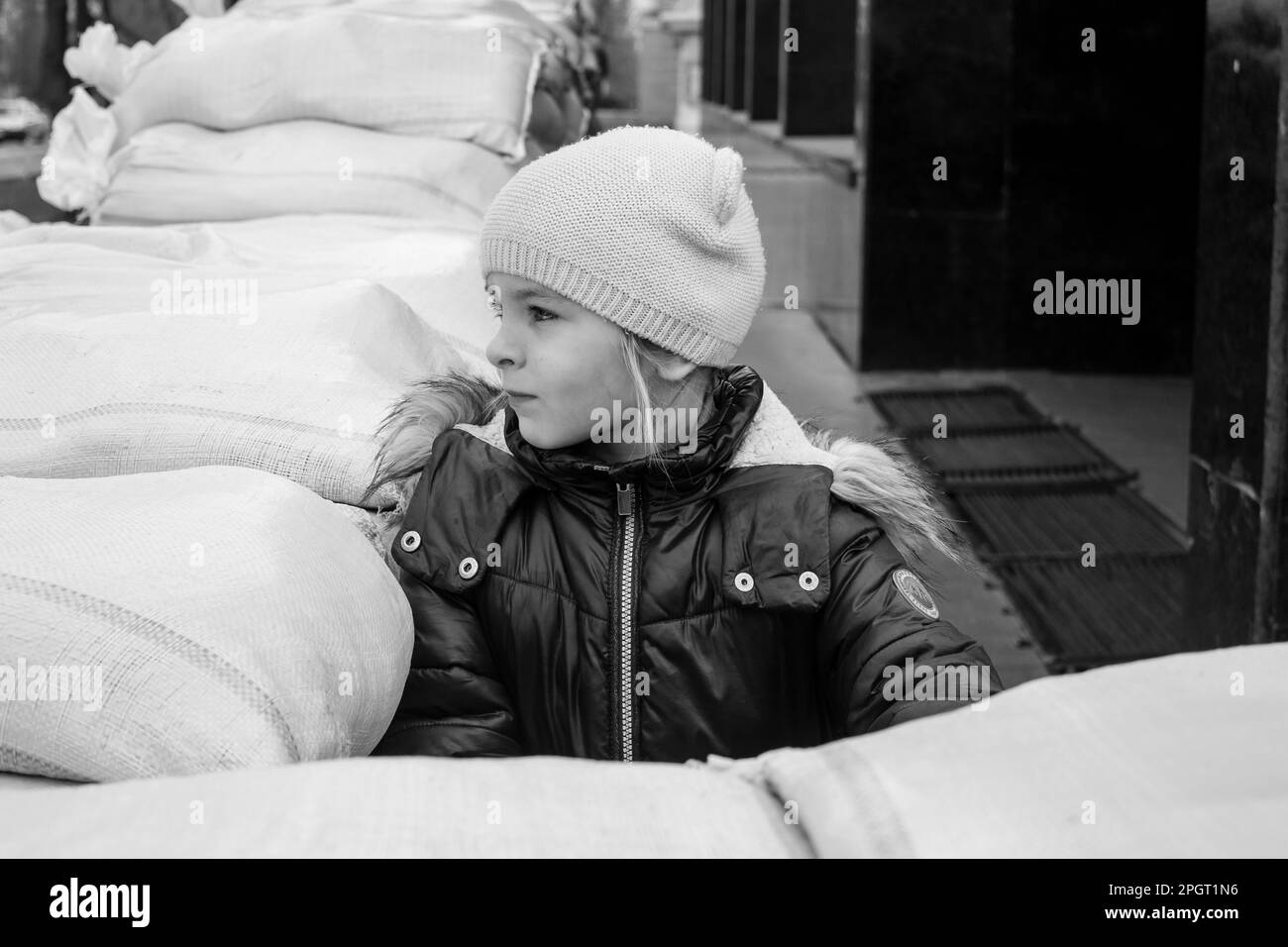 Portrait eines jungen Mädchens, das Spaß hinter einer Schutzwand mit Sandsäcken hat, ist eines ...
