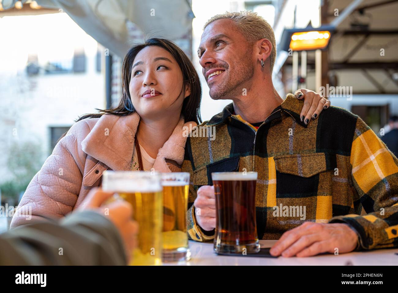 Zwei Freunde im Pub trinken Bier, ein junges, multiethnisches Paar mit ...