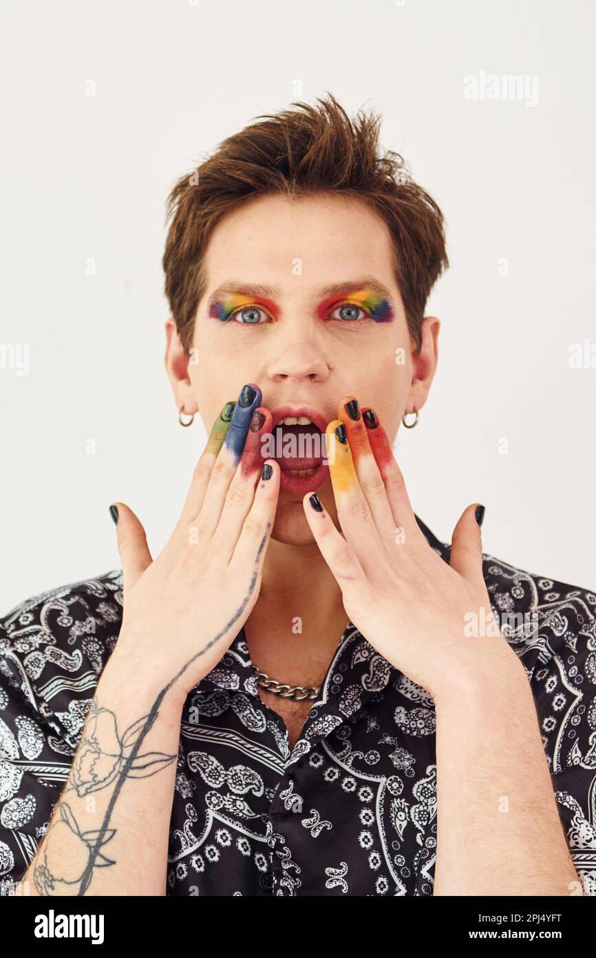 Ein junger schwuler Mann steht im Studio und posiert für eine Kamera ...