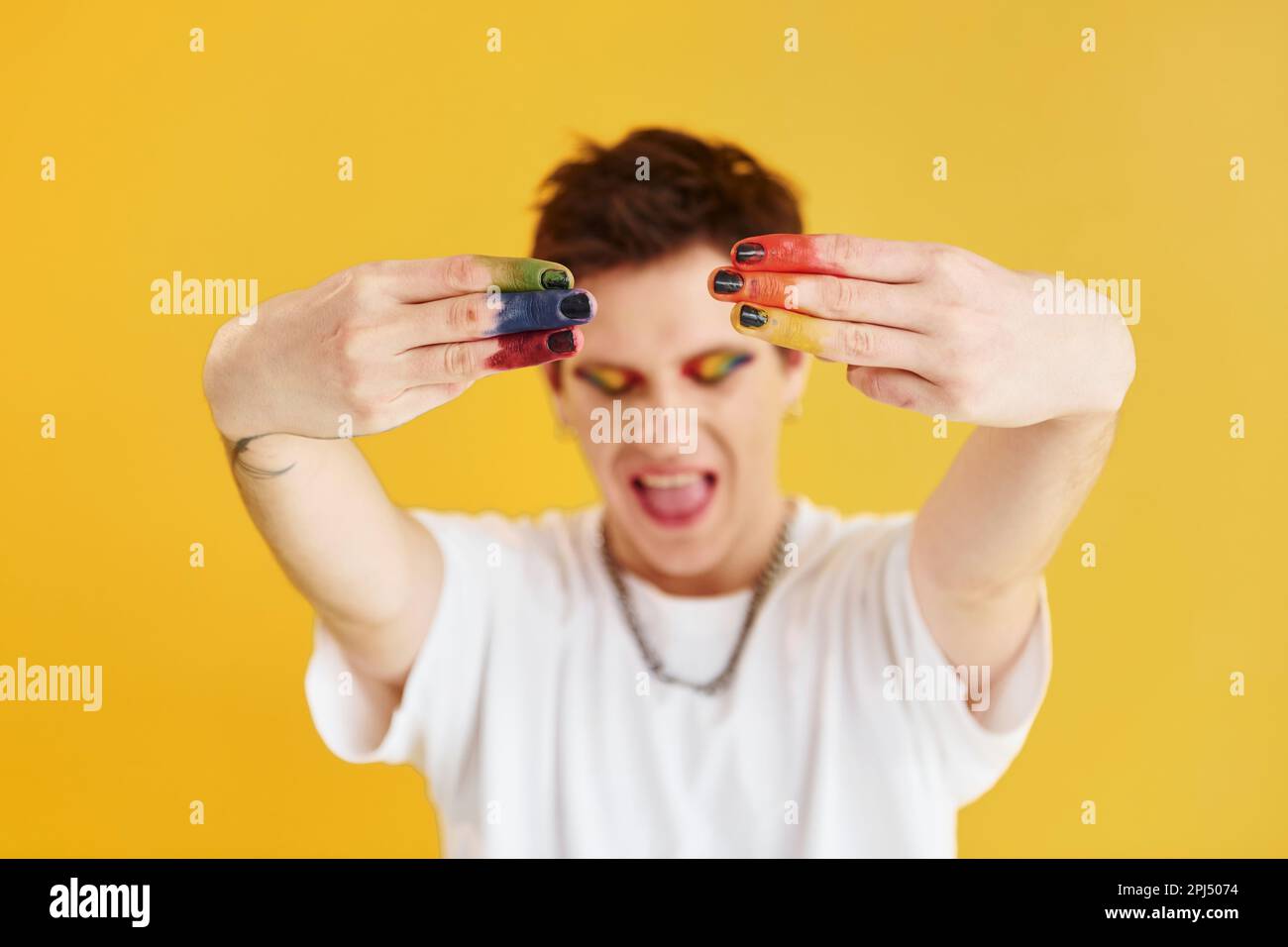 Ein junger schwuler Mann steht im Studio und posiert für eine Kamera ...