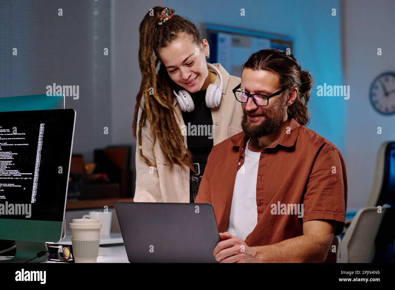 Zwei glückliche junge Programmierer, die sich den Laptop-Bildschirm mit ...