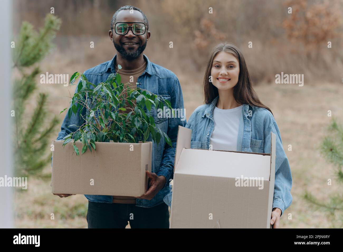 Eine glückliche junge Familie zieht in ein Haus. Ein schwarzer Mann und ...