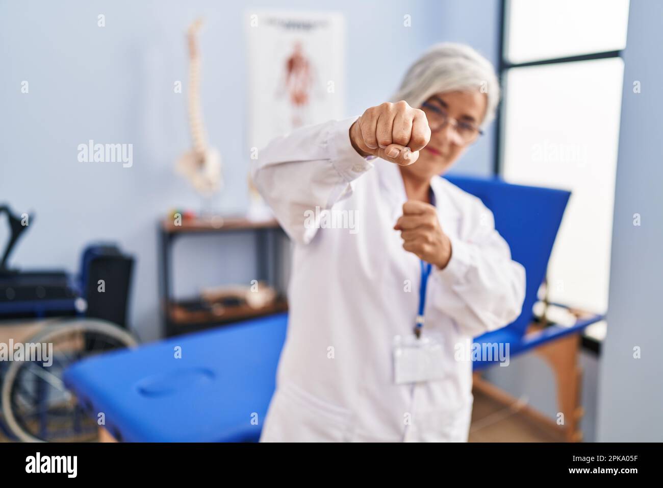 Mittelalterliche Frau mit grauen Haaren, die in der Schmerzheilungsklinik arbeitet, schlägt ...