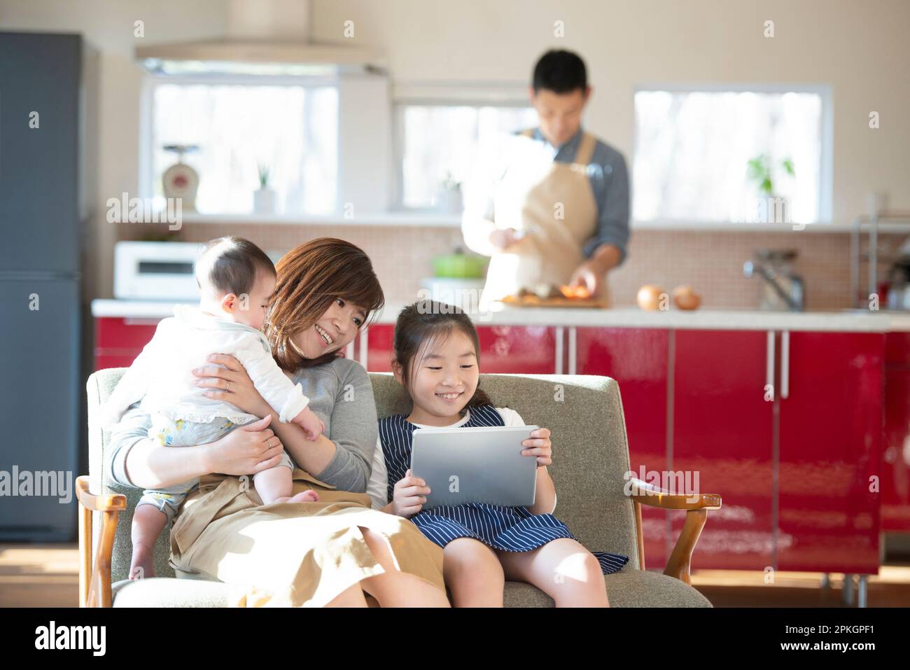 Eltern und Kinder, die auf dem Sofa sitzen und auf einen Tablet-PC ...