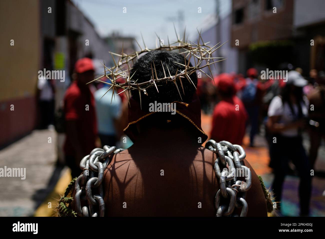 A penitent wearing a crown of thorns and chains with cacti stuck to his ...