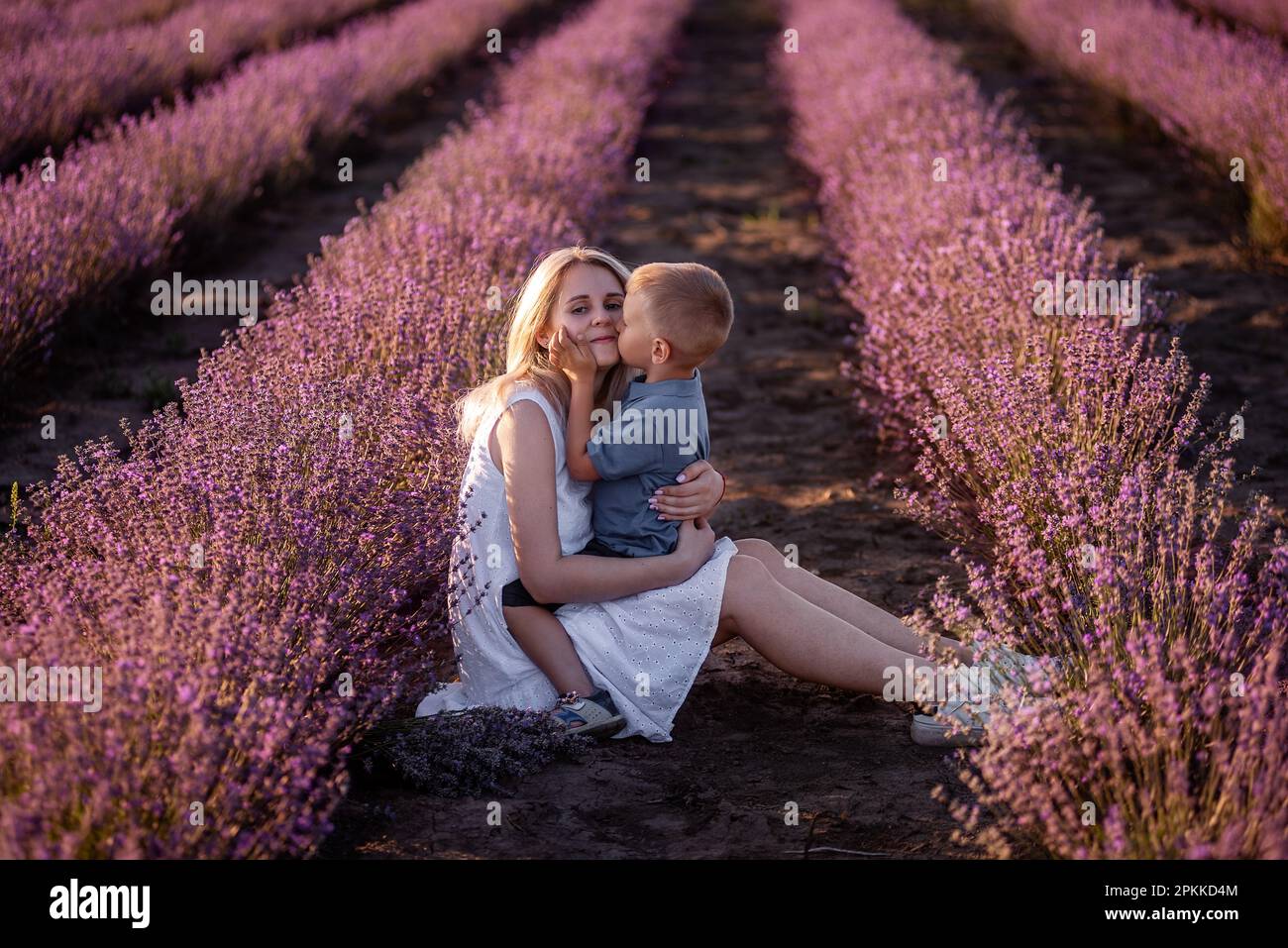 Ein Porträt von blonder Mutter mit kleinem Sohn sitzt im violetten ...
