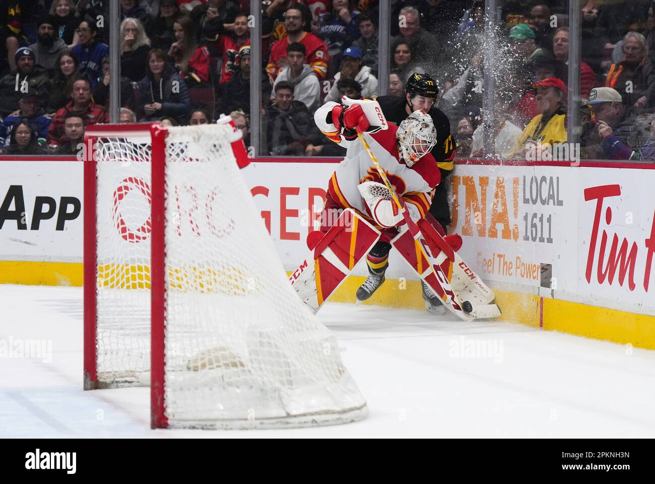 Calgary Flames goalie Jacob Markstrom, front, plays the puck outside the trapezoid in front of ...