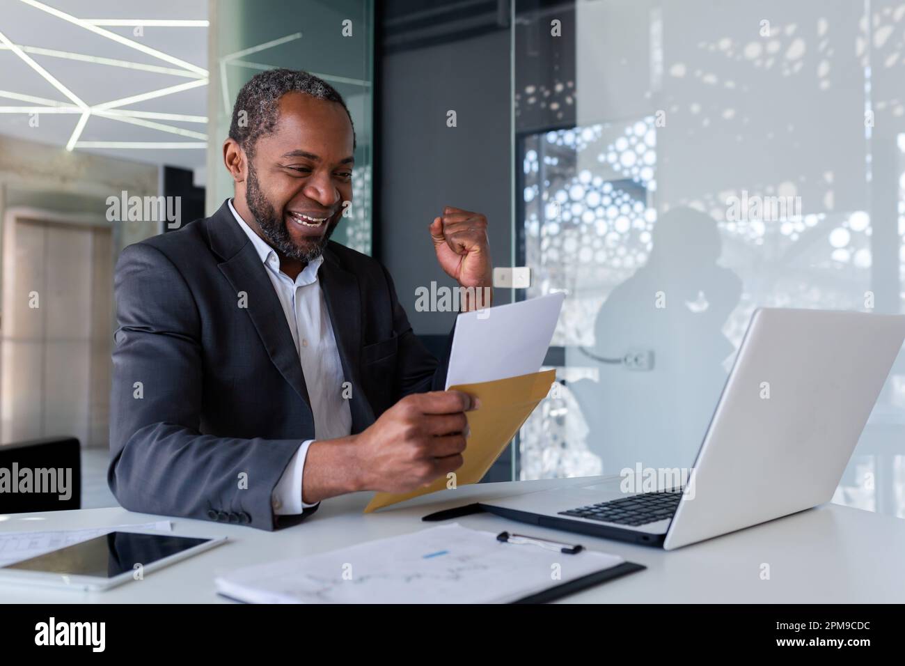 Ein afroamerikaner im Anzug sitzt im Büro am Schreibtisch und ist ...