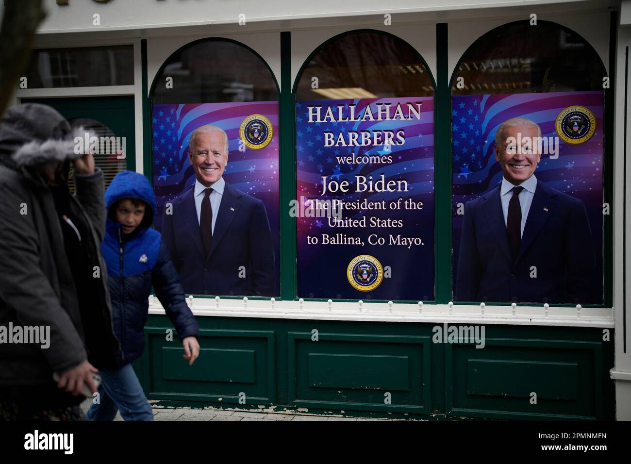 Pedestrian walk in the rain past a shop window with portraits of ...