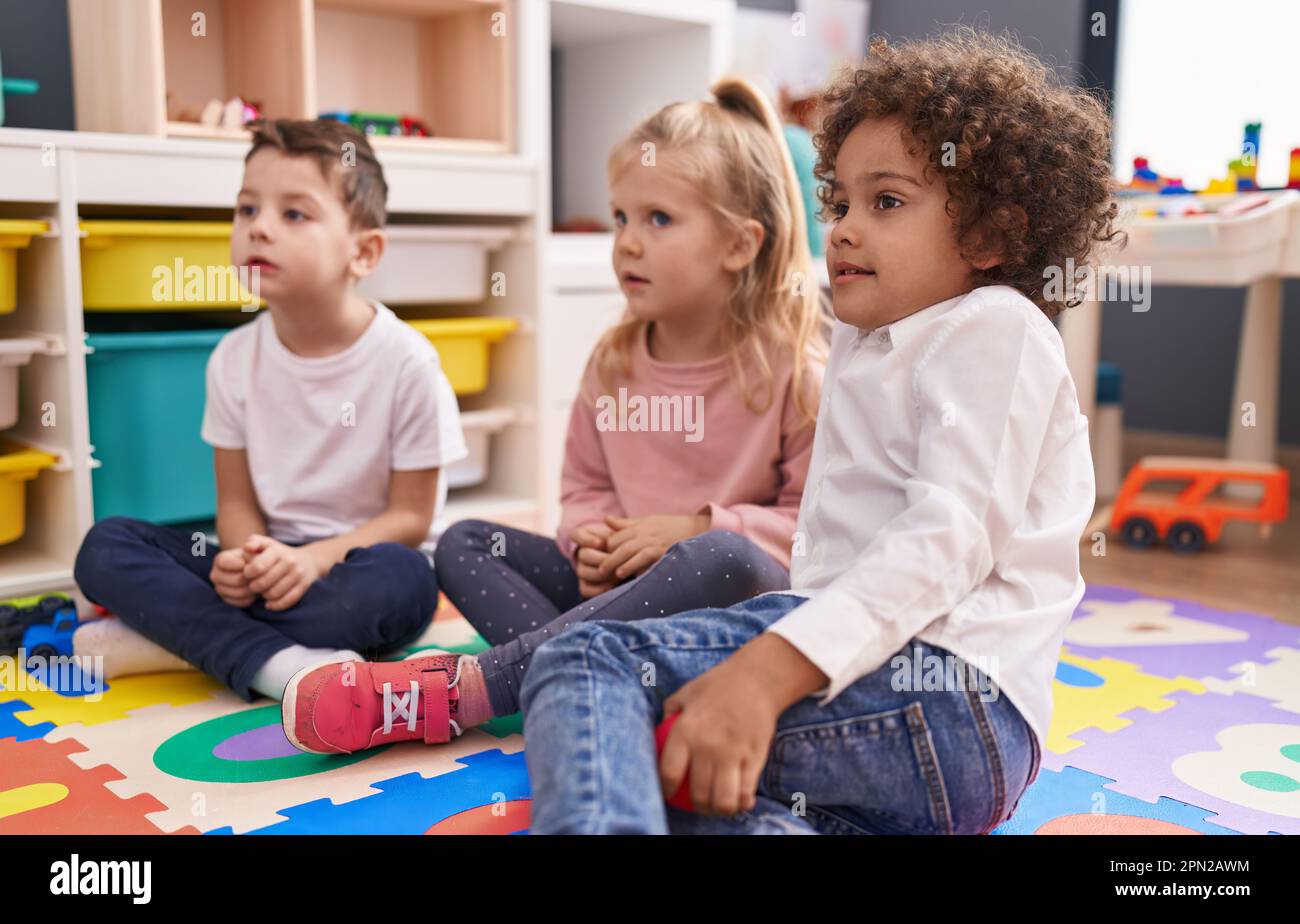 Gruppe von Kindern, die auf dem Boden sitzen, mit entspanntem Ausdruck ...