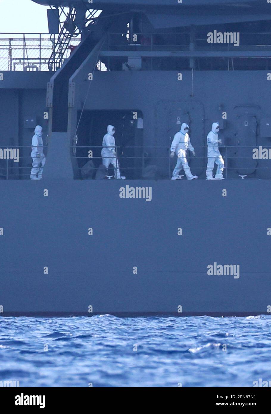 Crew members in a white protective suit aboard the Chihaya, a submarine ...