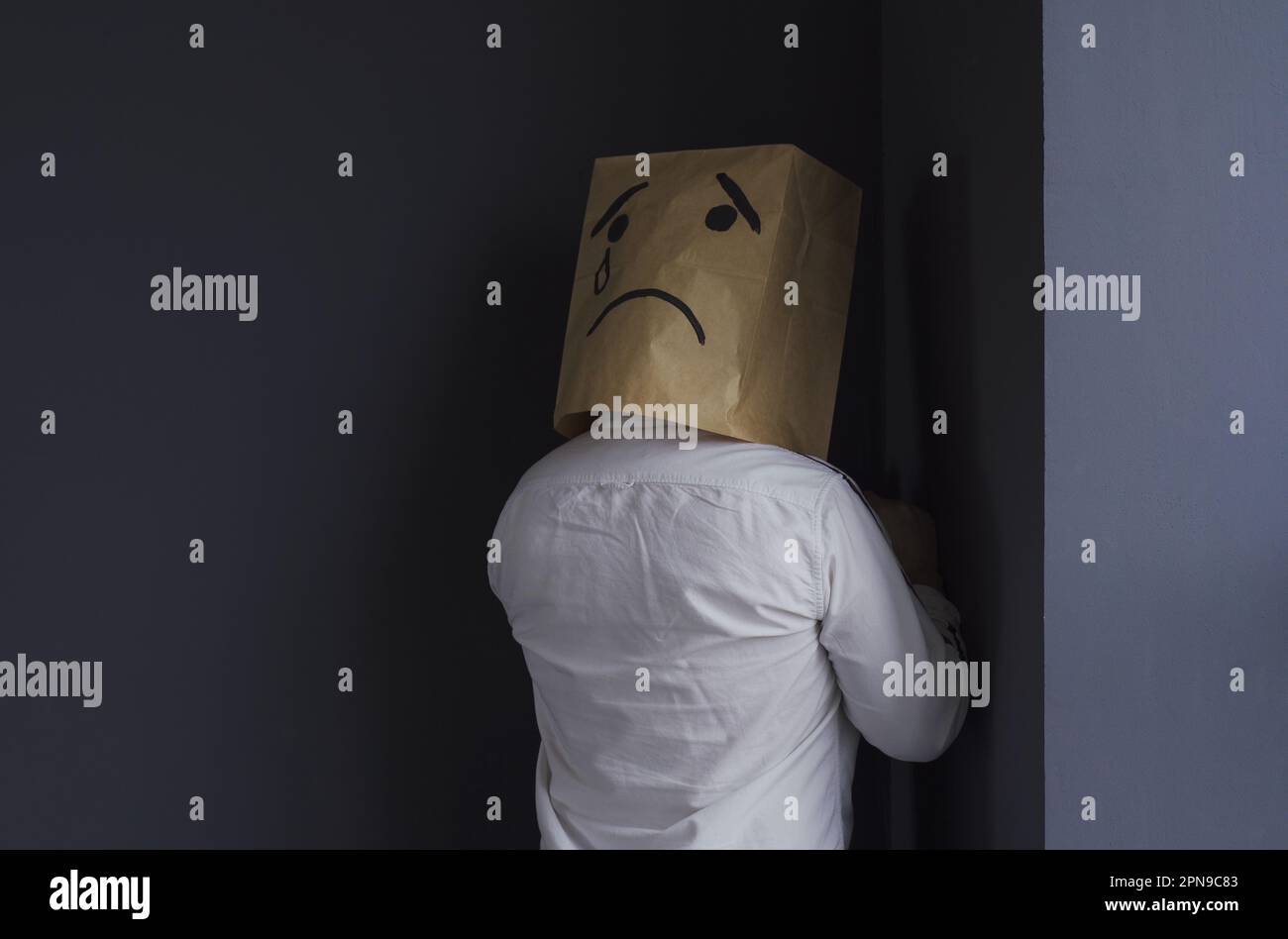Ein trauriger Mann in einem weißen Hemd mit einer Tasche auf dem Kopf, mit einem gezogenen ...