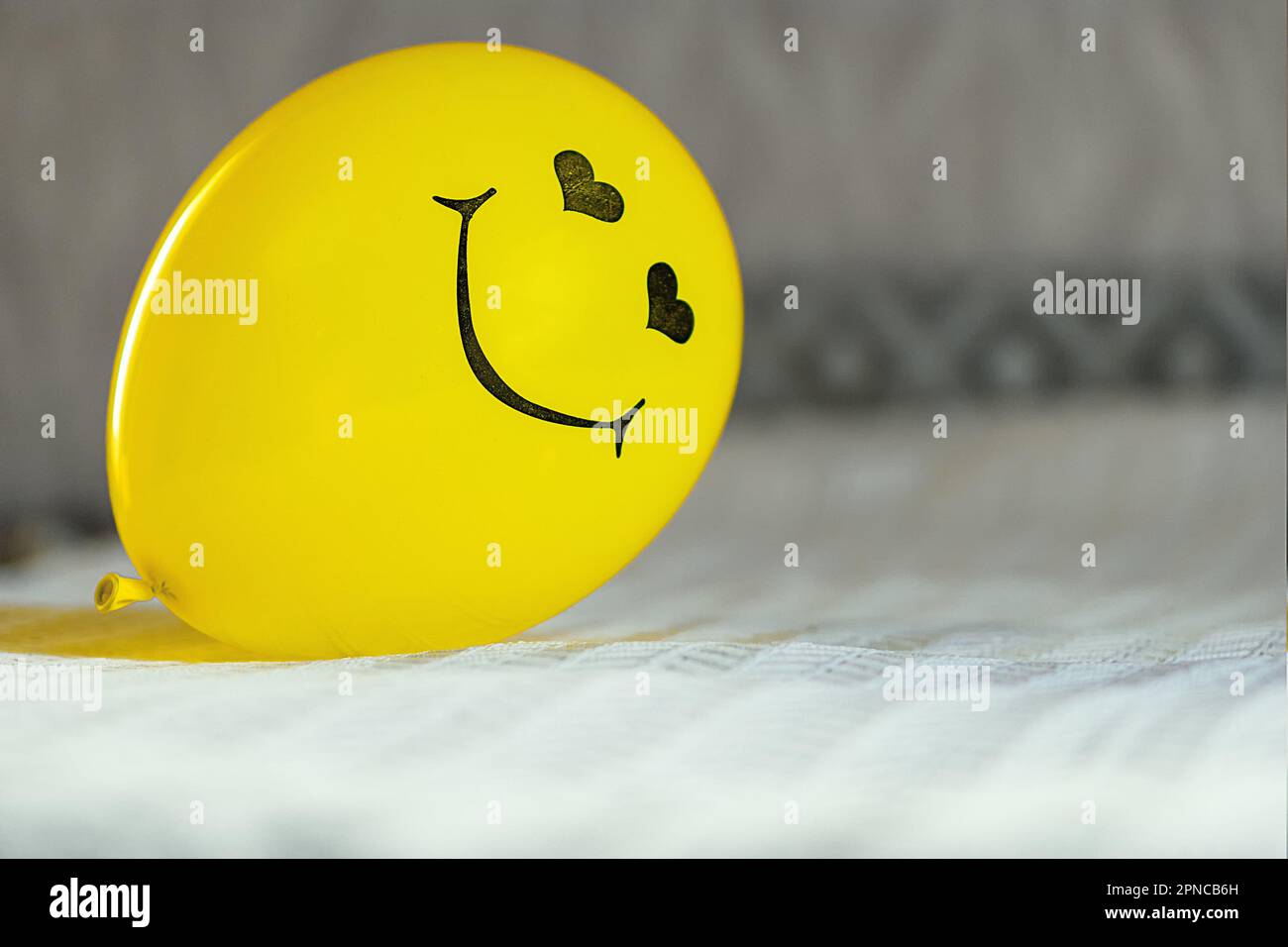 Gelber Ballon mit einem Lächeln und Augen in Form von Herzen, auf der ...