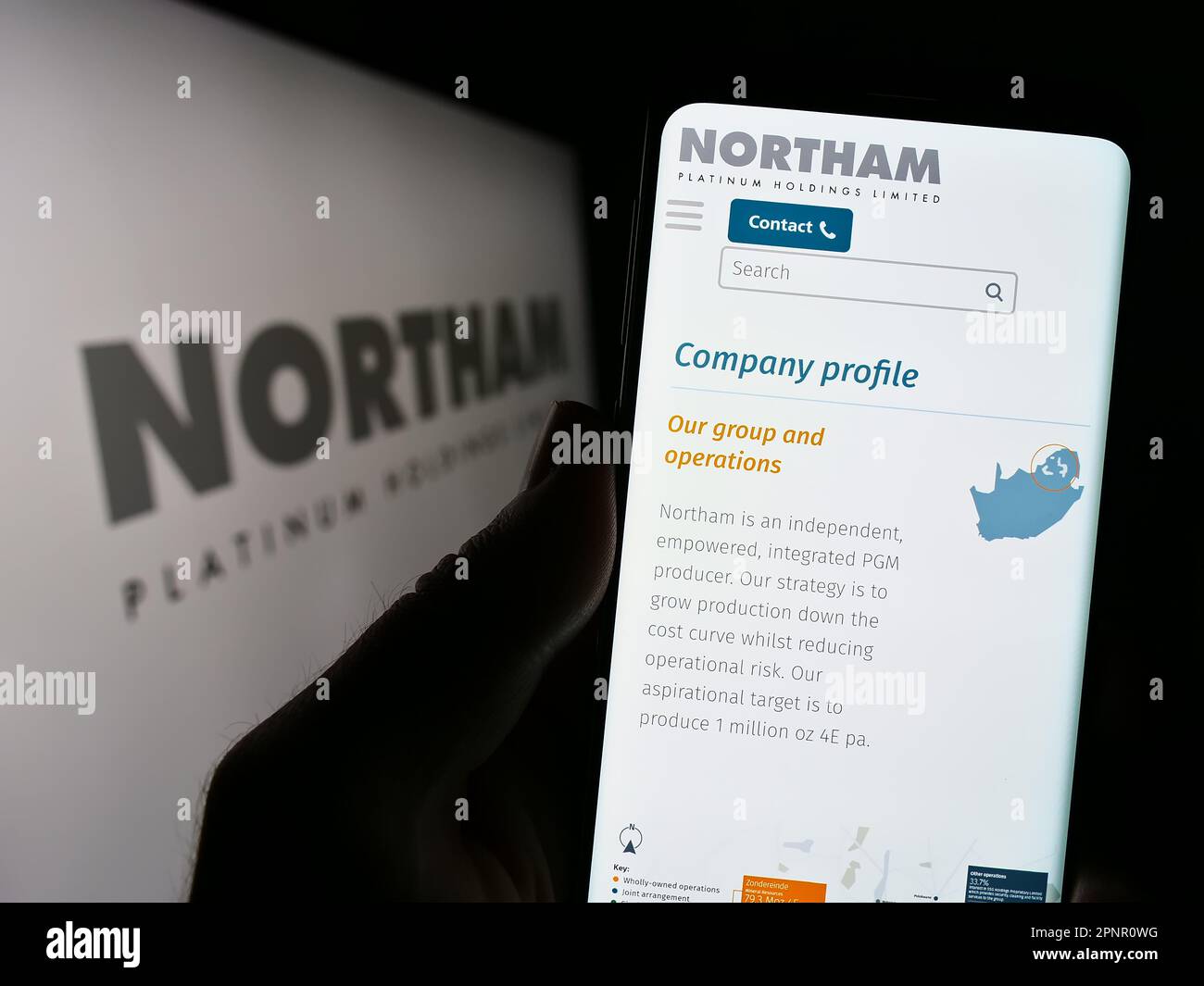 Person, die ein Mobiltelefon mit der Website der Firma Northam Platinum ...