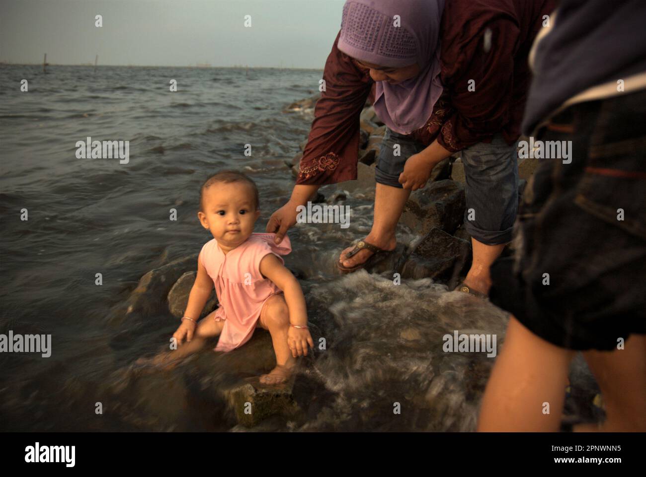 Eine Familie, die Freizeit am Strand hat, da sie sich um ein Baby in ...