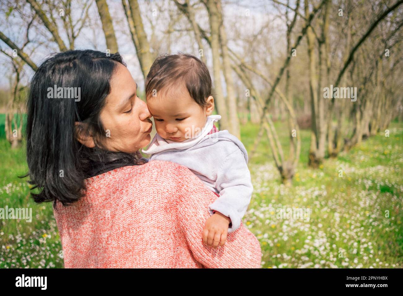 Glückliche Mutter und kleine Tochter stehen zusammen unter einem Baum ...
