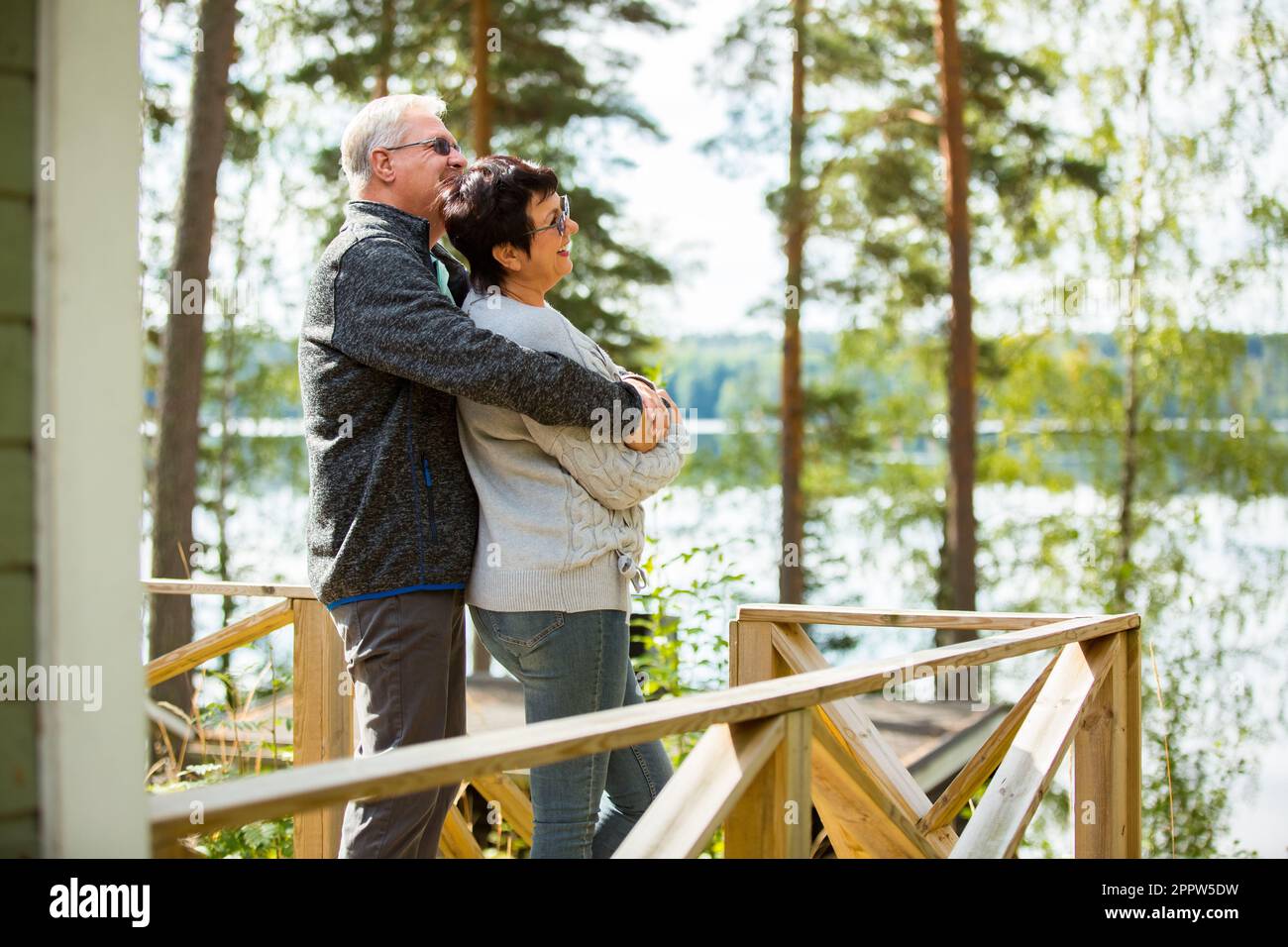 Reifes Paar, das auf der Veranda steht und sich umarmt. Sie lächeln und ...