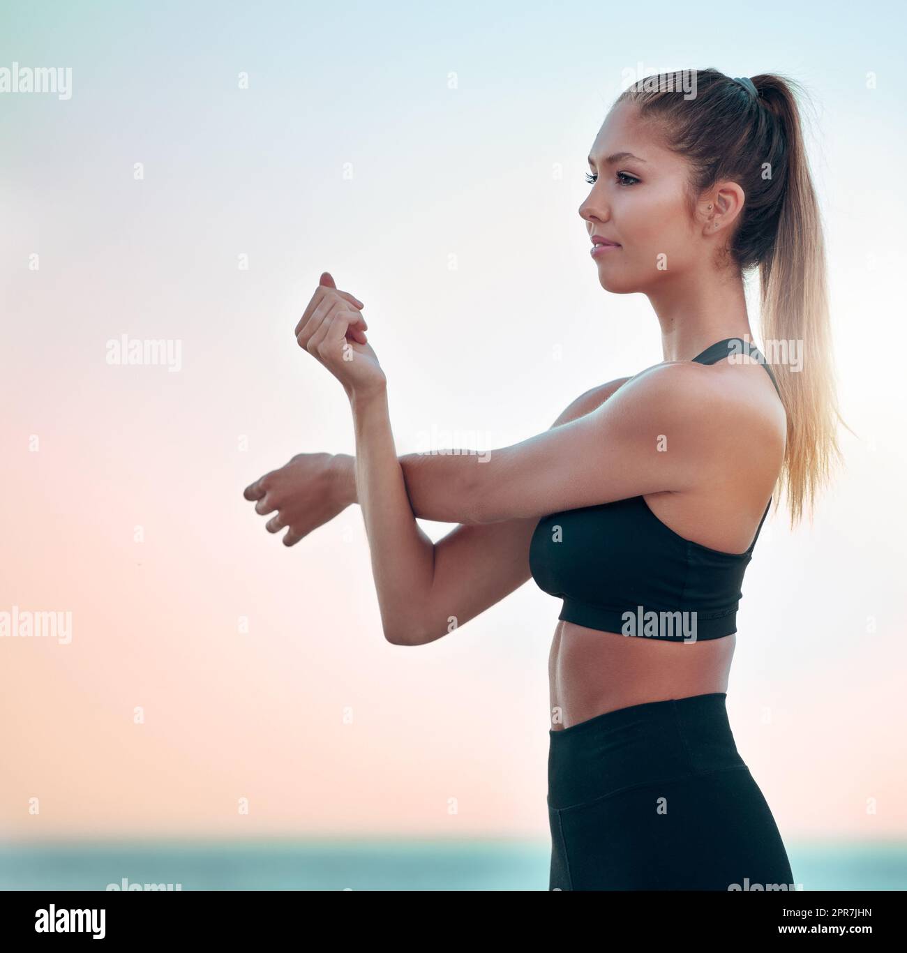 Wunderschöne Frau, die am Strand Yoga trainiert. Junge Sportlerin dehnt ...