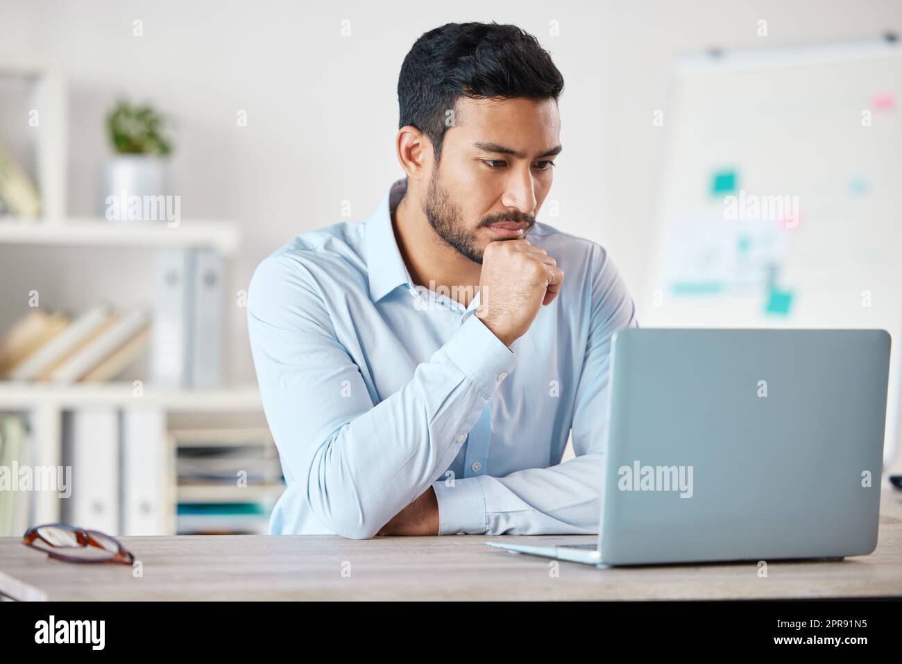 Junger, ernster Geschäftsmann aus gemischten Rassen, der an einem Tisch ...