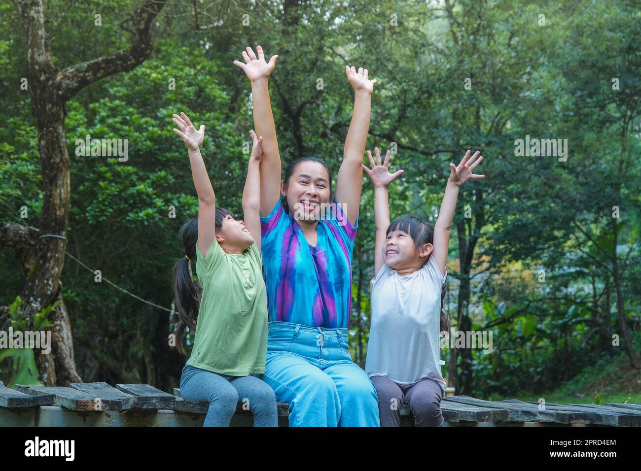 Glückliche junge Mutter mit kleinen Mädchen, die im Sommer auf einer ...