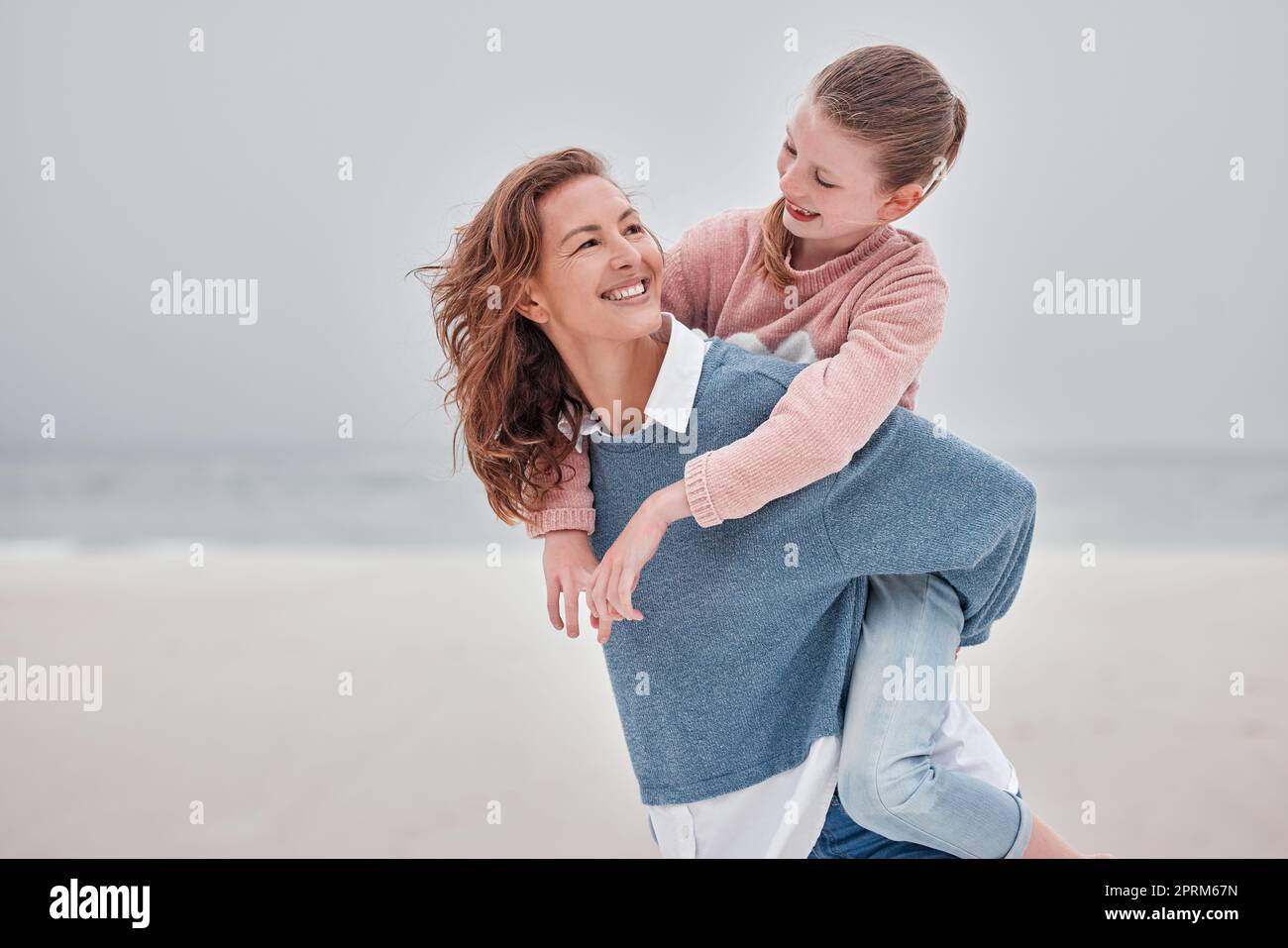 Mutter, Kind und Huckepack für die Liebe am Strand mit Lächeln für eine schöne Zeit, in der sich ...