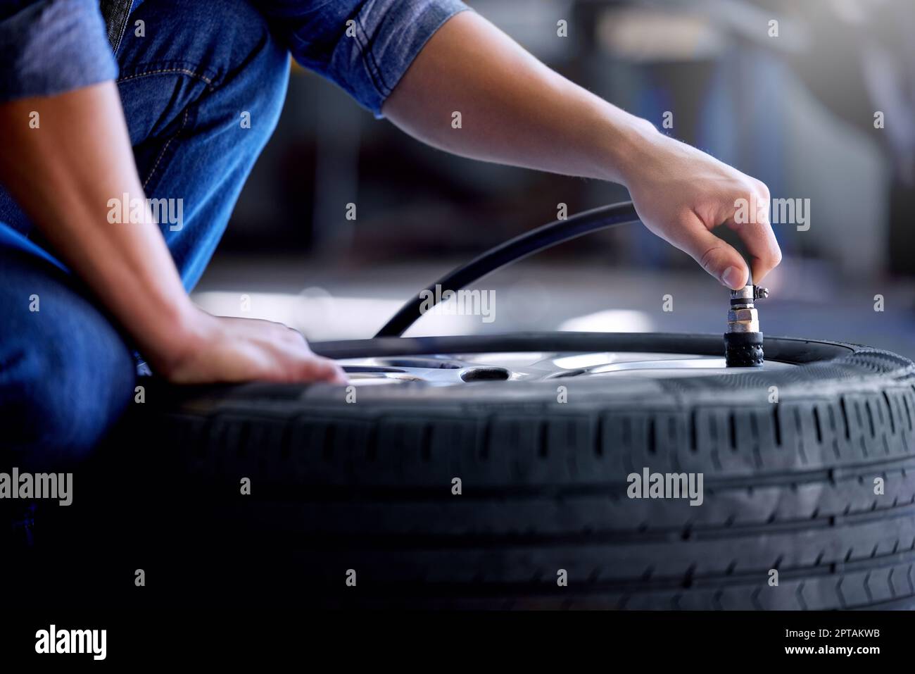 Luftdruck, Reifen und Mechaniker arbeiten in der Garage mit Pumpe in der Hand. Mann im ...