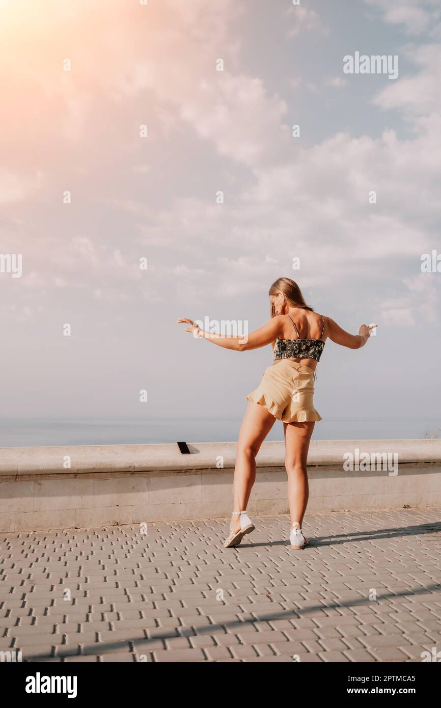 Frauen-Sommertanz. Silhouette einer glücklichen Frau, die tanzt, sich dreht und ihre Hände zum ...