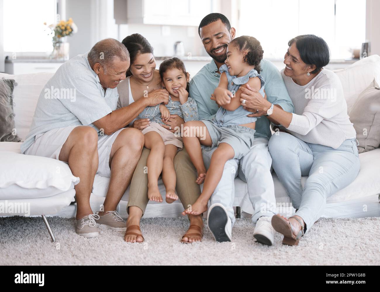 Eine Familie aus mehreren Generationen, die im Garten zuhause nahe beieinander sitzt. Fröhliche ...