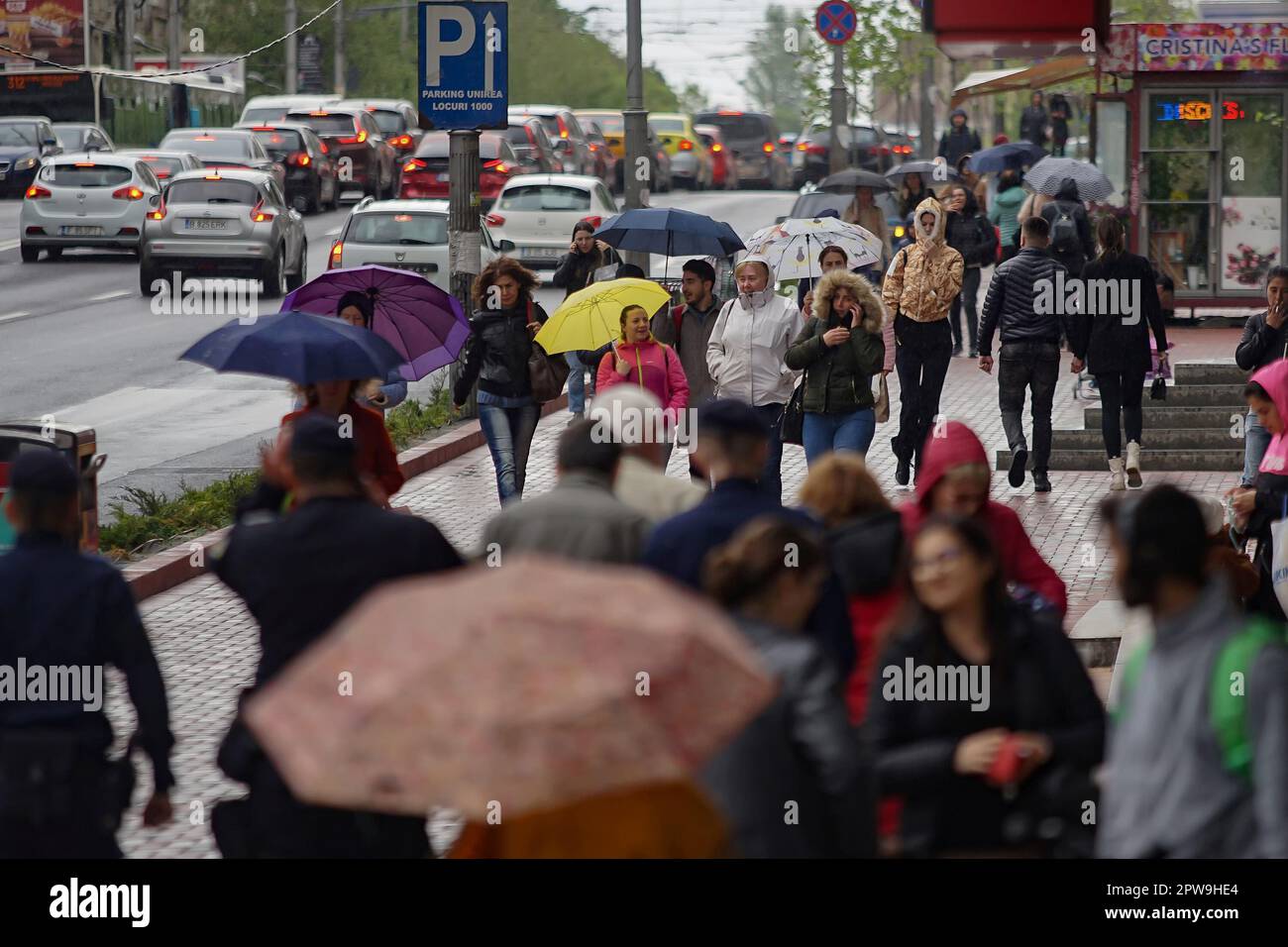 Bukarest, Rumänien. 27. April 2023: Menschen mit Sonnenschirmen laufen ...