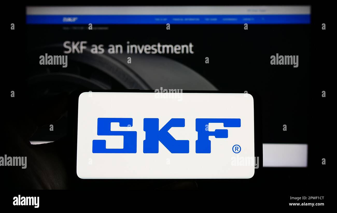 Person, die ein Mobiltelefon mit dem Logo des schwedischen Lagerherstellers SKF ab auf dem ...