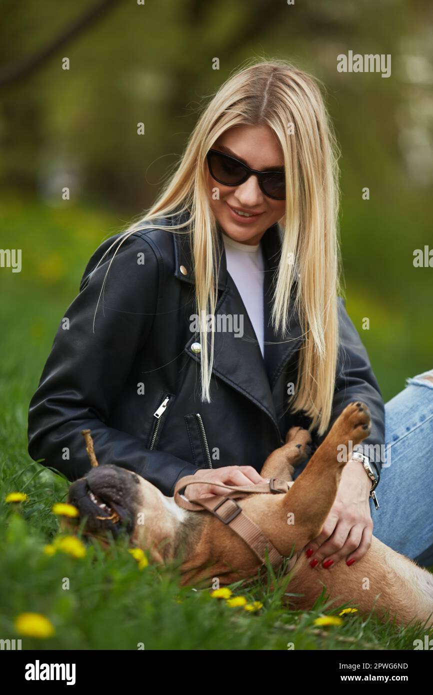 Blonde Frau, die draußen mit ihrem Haustier spielt. Fröhliche junge ... Blonde Frau, die draußen mit ihrem Haustier spielt. Fröhliche junge ...