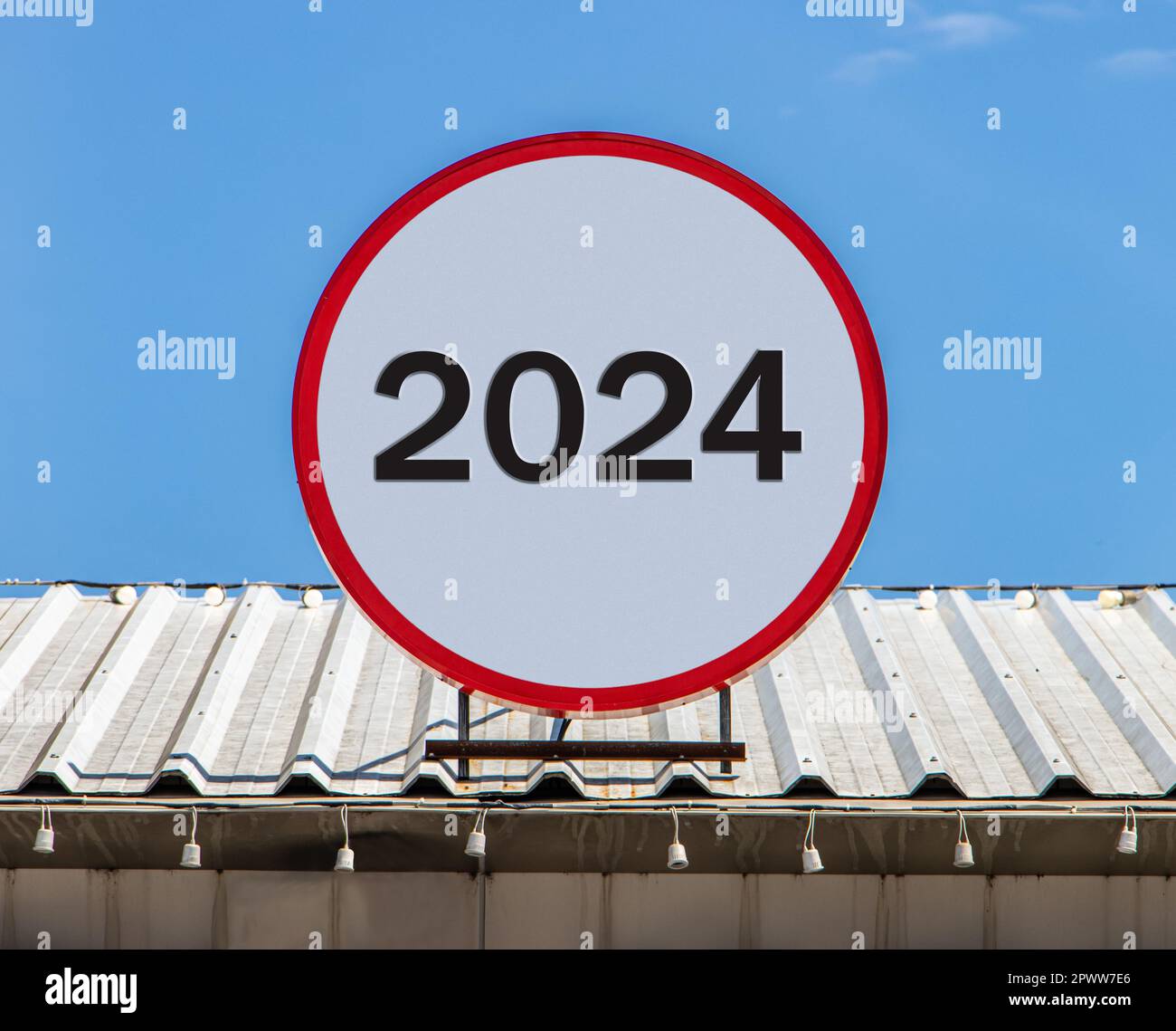 Auf einem Dach befindet sich eine kreisförmige Plakatwand mit der Nummer 2024. Begrüßung für ...