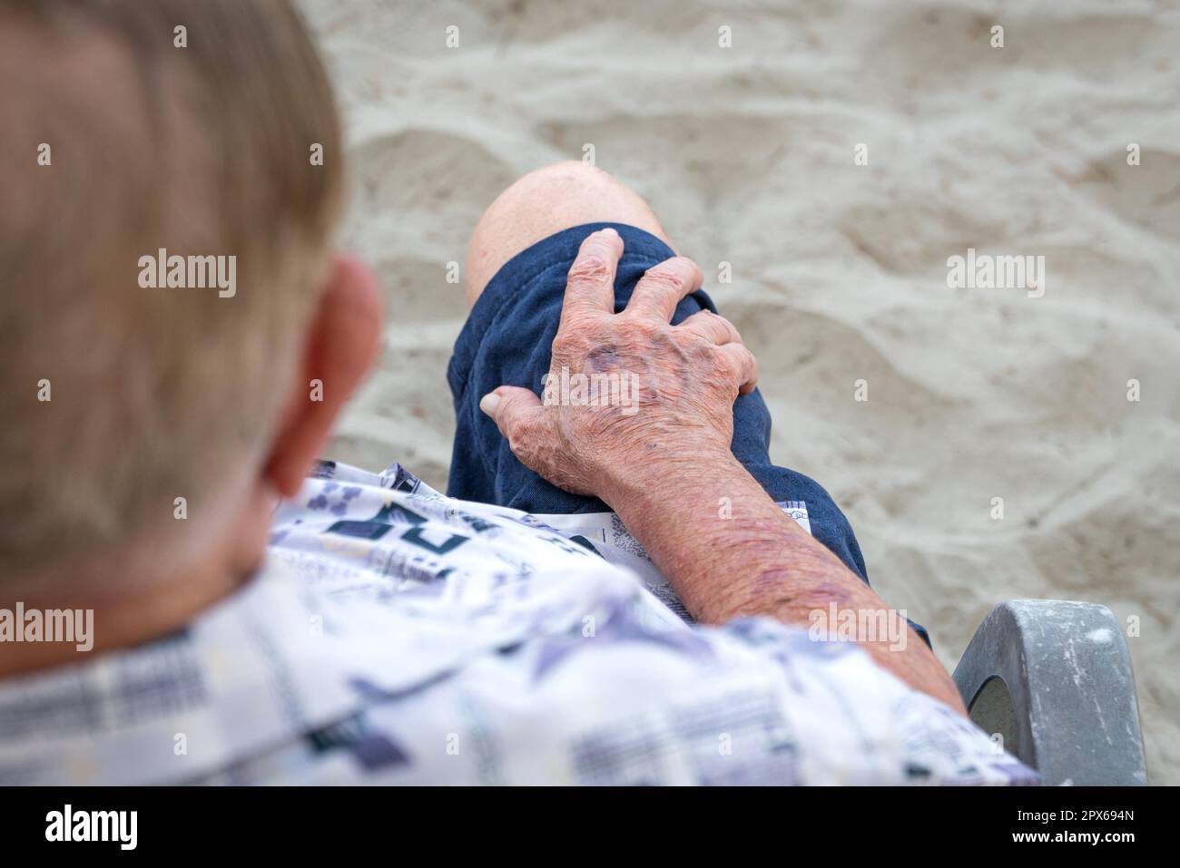 Älterer Mann mit der Hand auf dem Schoß. Nahaufnahme der Haut mit ...