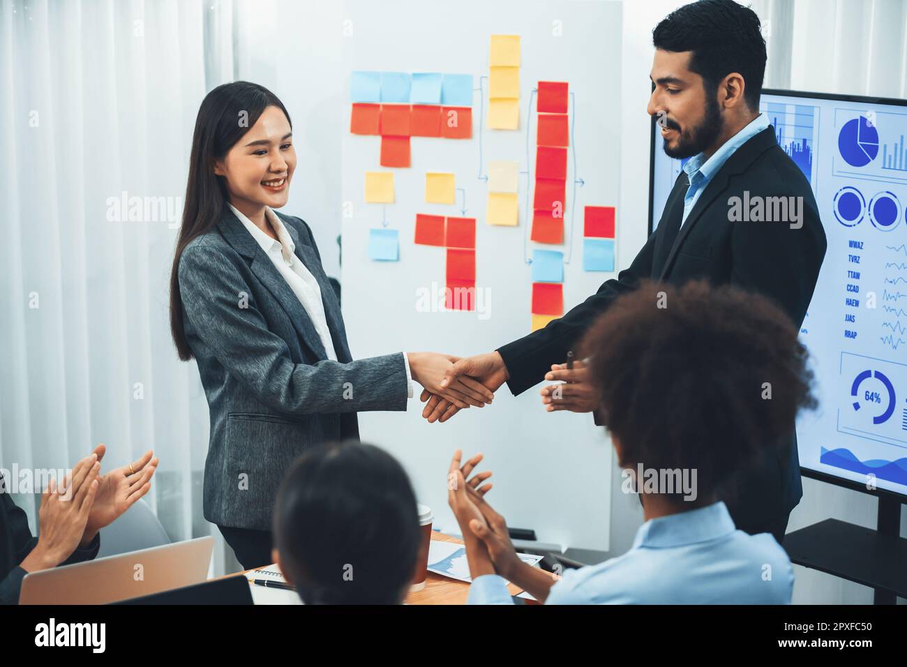 Ein vielseitiger Kollege feiert mit einem Händedruck und Teamwork am ...