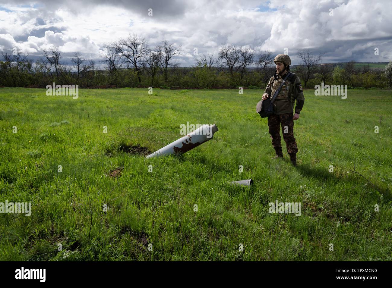 Ukraine. 25. April 2023. Ein ukrainischer Soldat steht neben einer nicht explodierten Rakete in ...