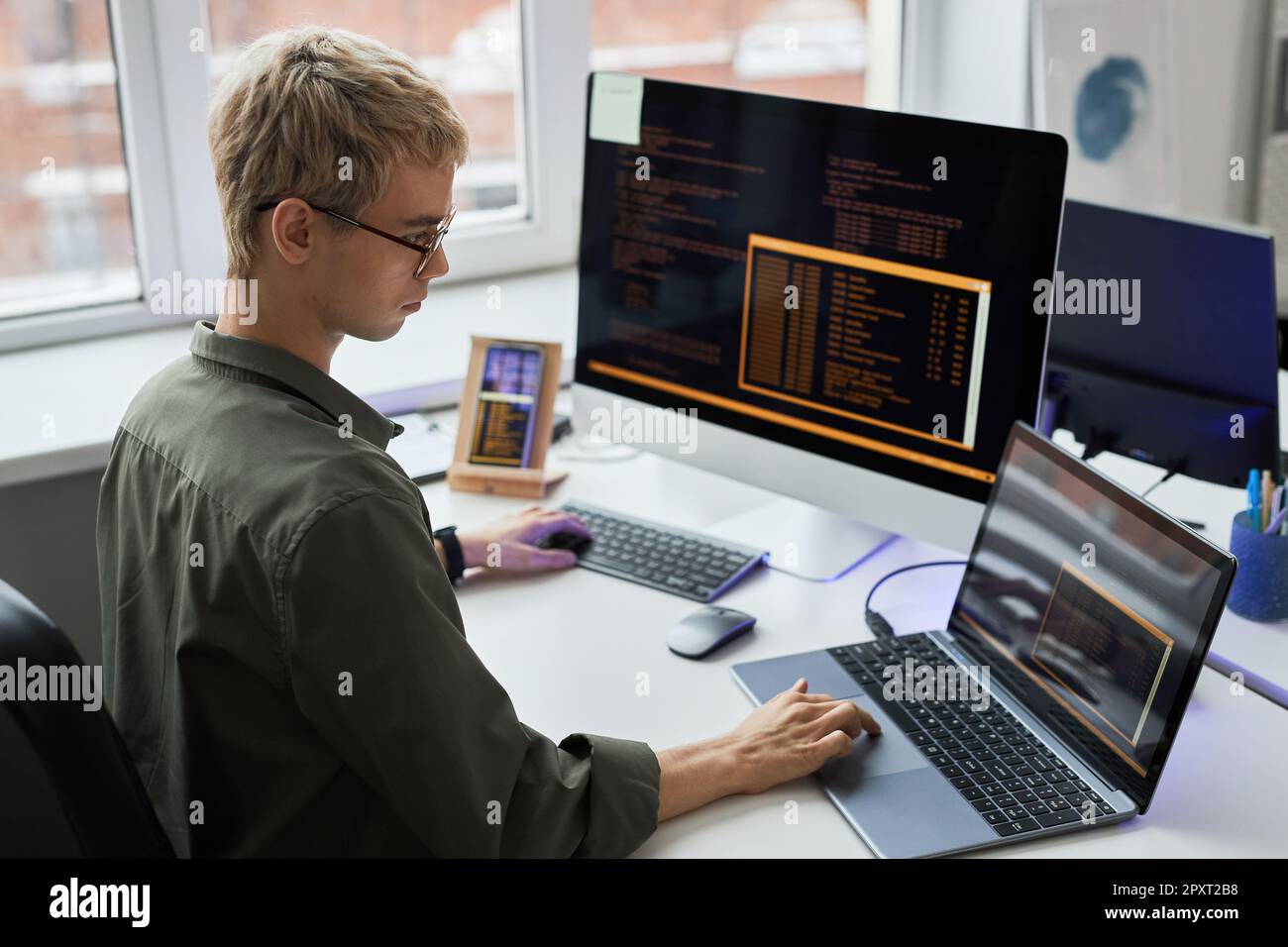 Rückansicht eines jungen Programmierers mit Brille, der während der ...