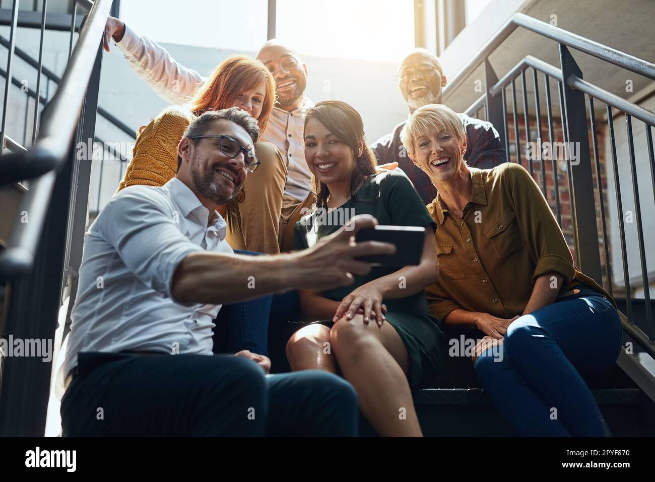 So sieht ein Team aus. Eine Gruppe von Kollegen, die draußen auf Treppen sitzen und zusammen ein ...