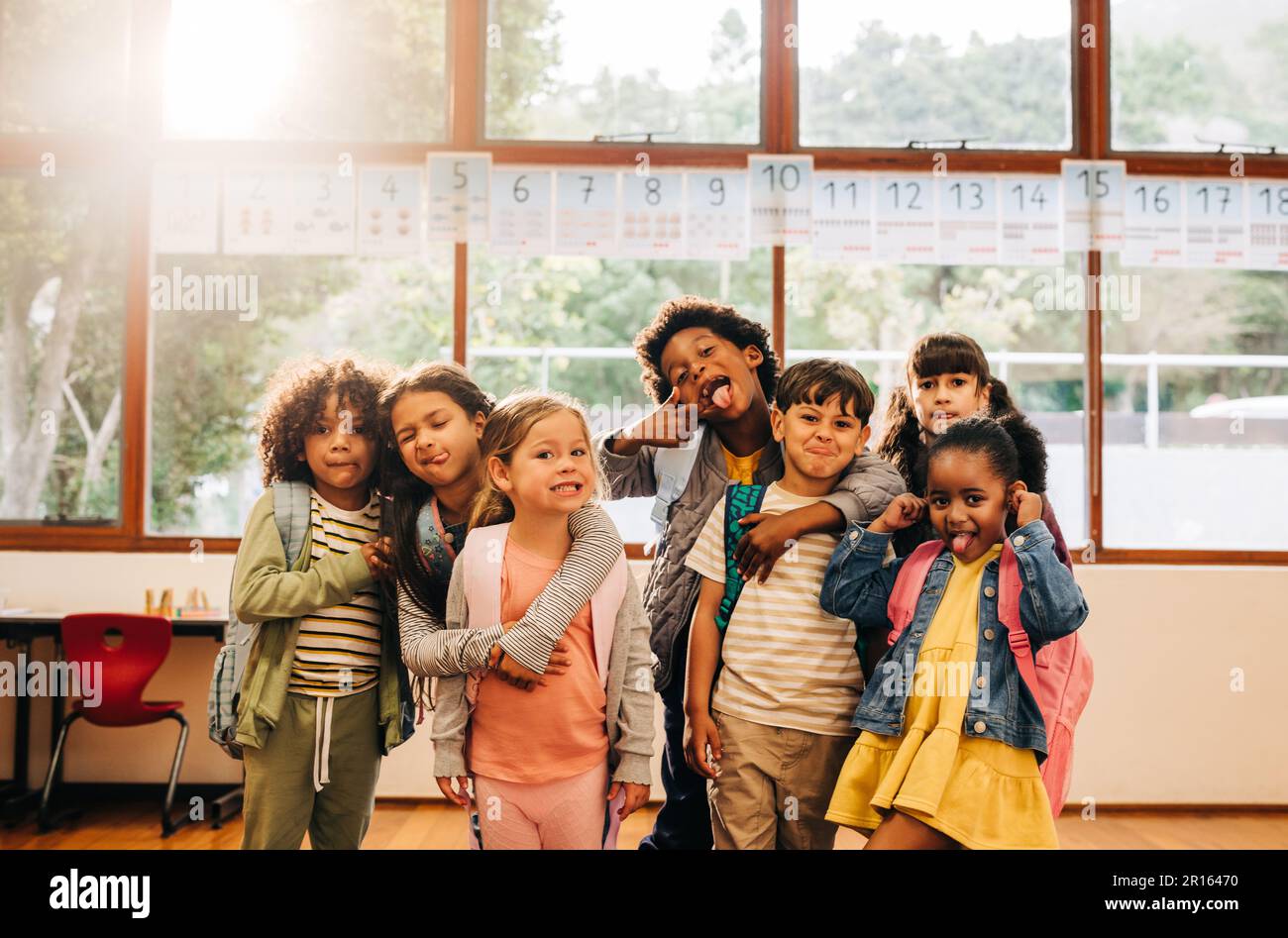 Junge Schüler stehen zusammen in einem Klassenzimmer und schauen mit ...