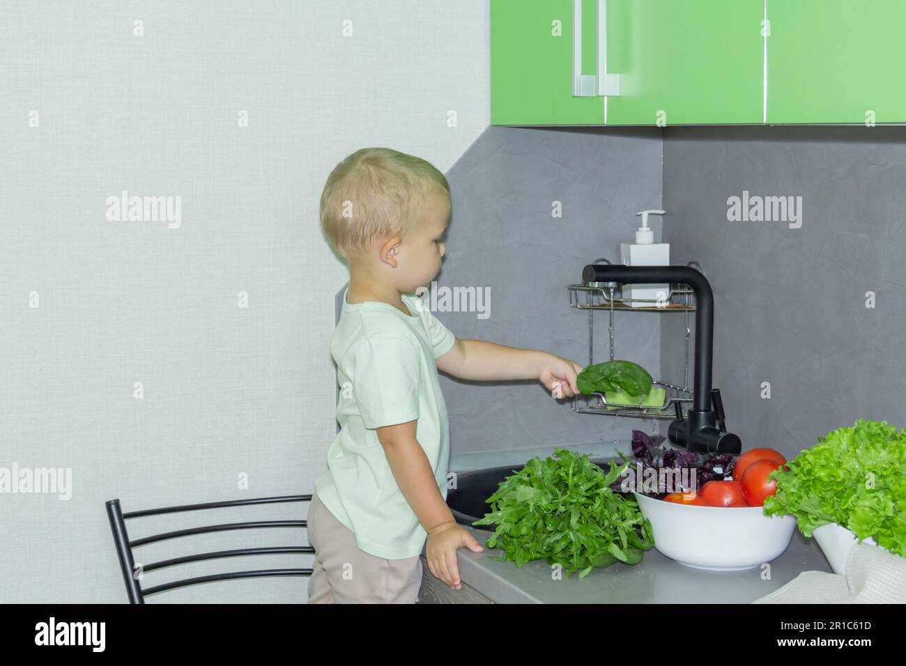 Ein kleiner Junge mit einem kurzen Haarschnitt hilft beim Kochen in der ...